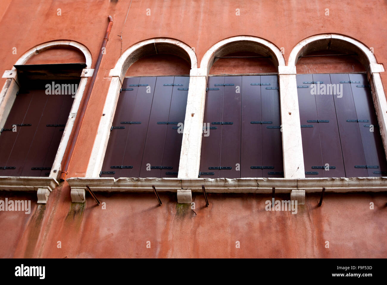 Four windows with wood shutters on an orange wall Stock Photo - Alamy