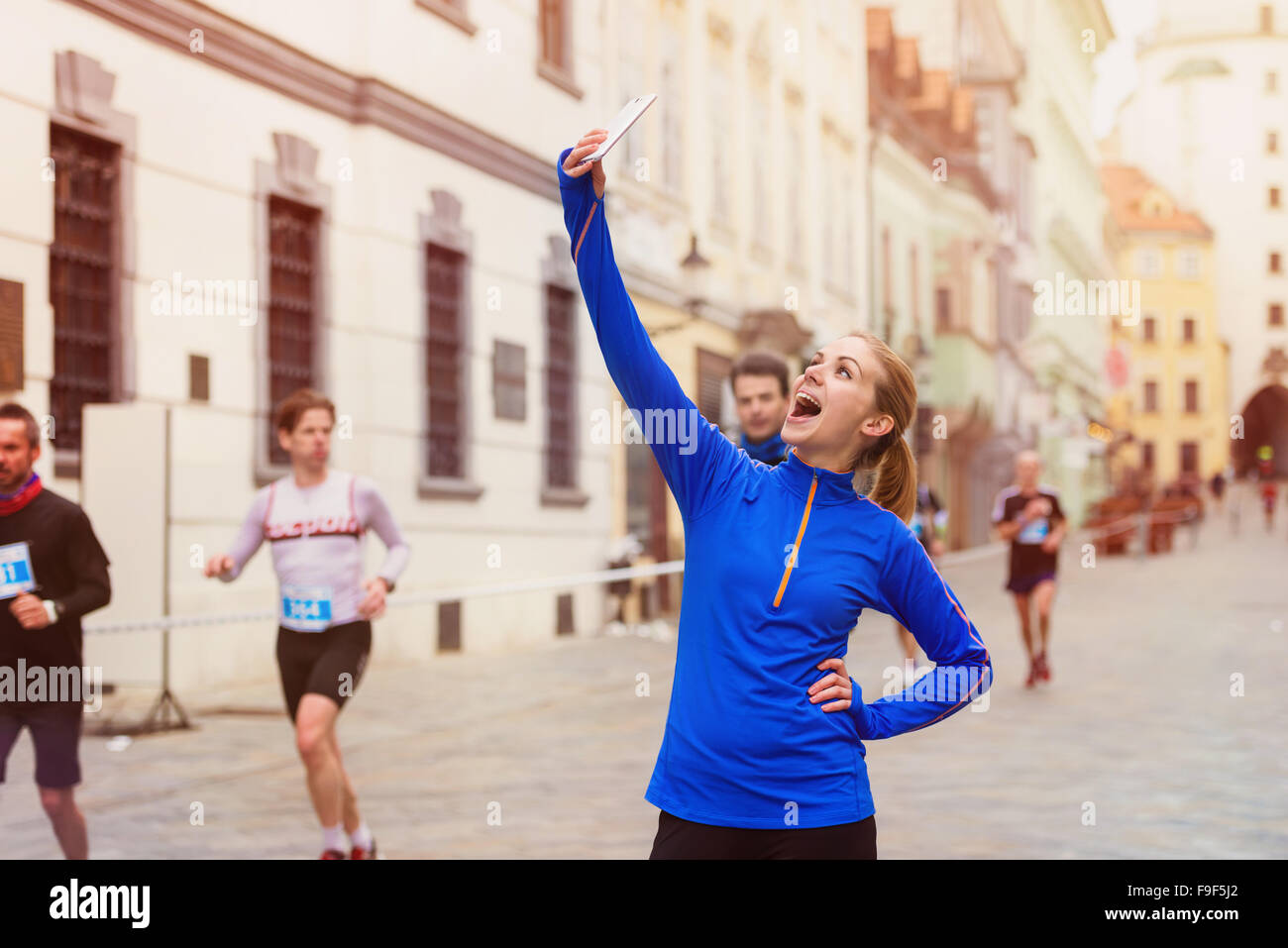 Beautiful young woman running in the city competition taking a selfie ...