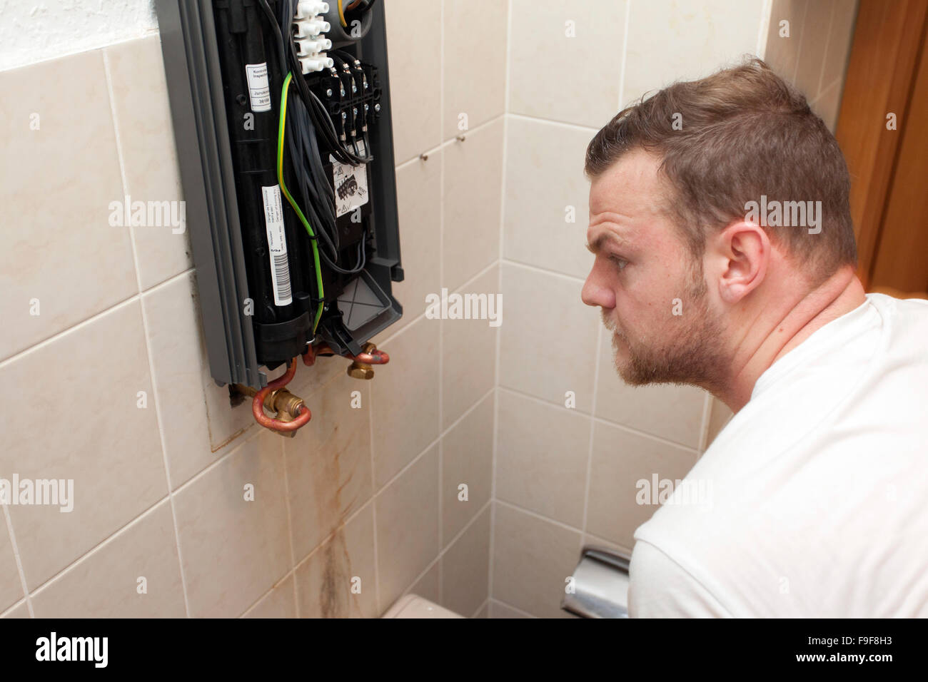 Plumber installs continuous-flow water heater in the bathroom Stock ...