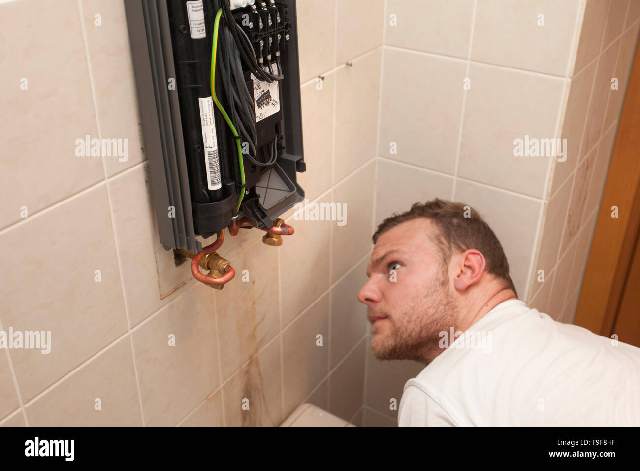 Plumber installs continuous-flow water heater in the bathroom Stock ...
