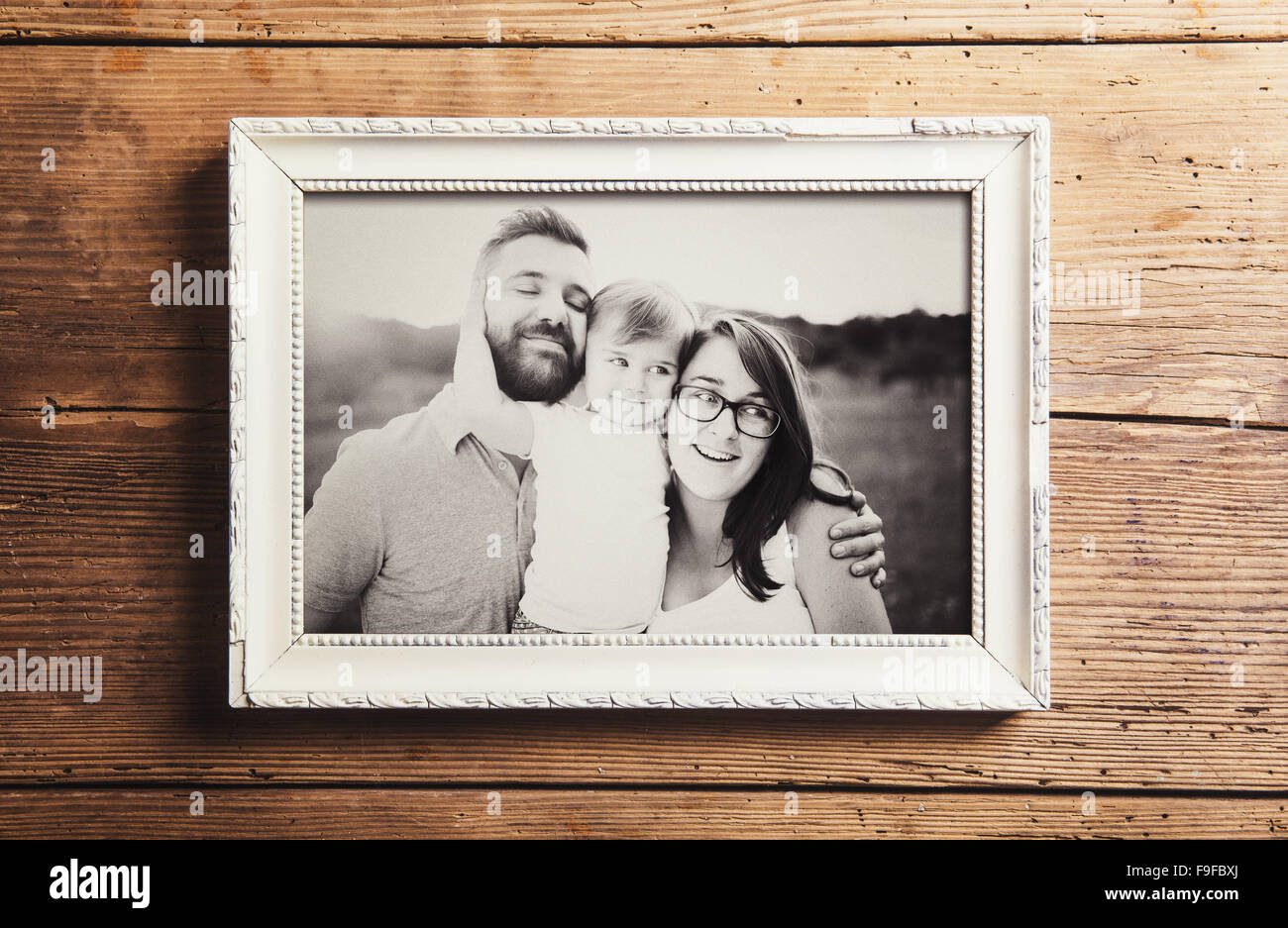 Family photo in white picture frame. Studio shot on wooden backgroung ...
