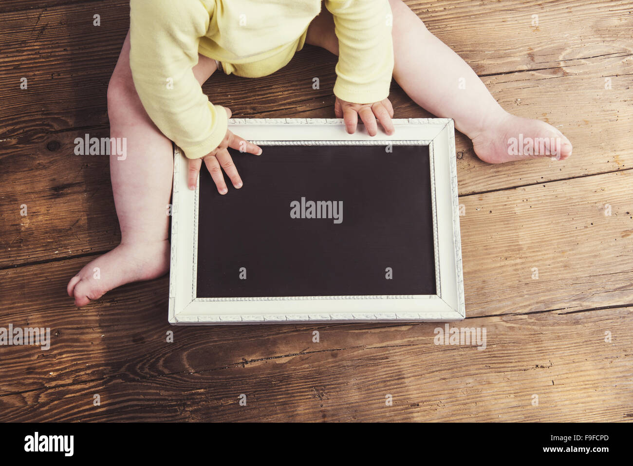 Little baby with empty picture frame on wooden background Stock Photo ...