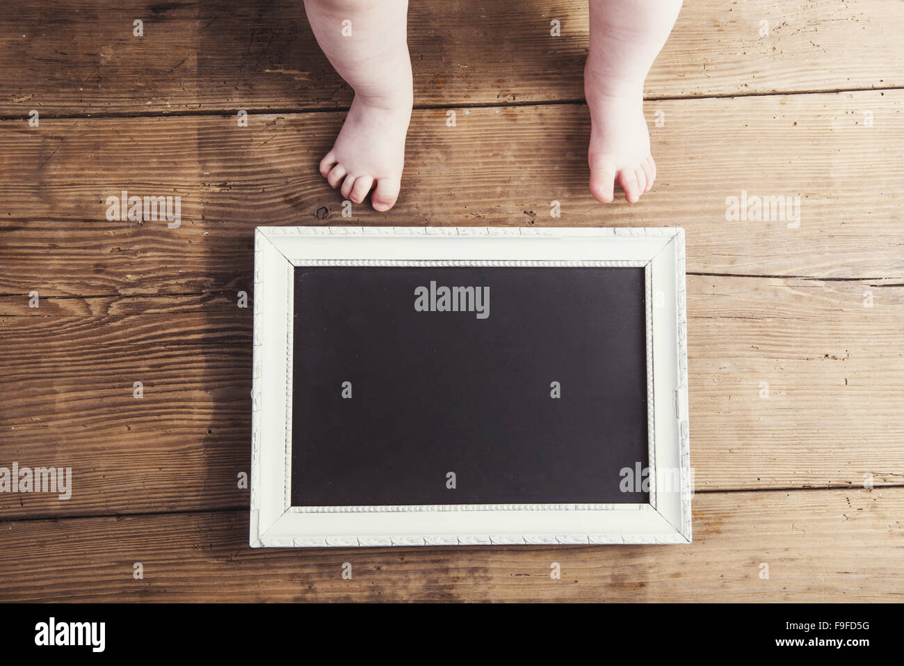 Little baby with empty picture frame on wooden background Stock Photo ...