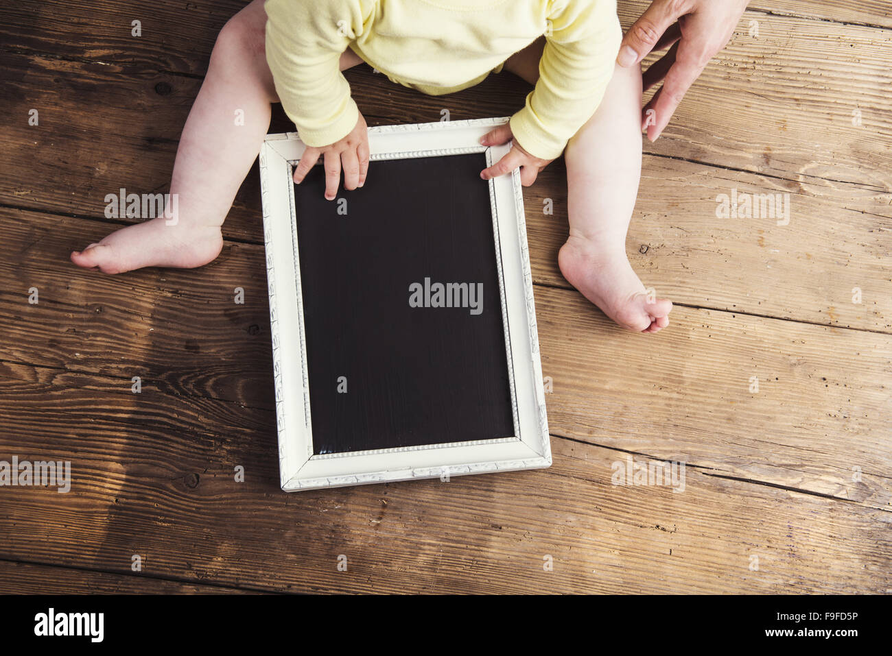 Little baby with empty picture frame on wooden background Stock Photo ...
