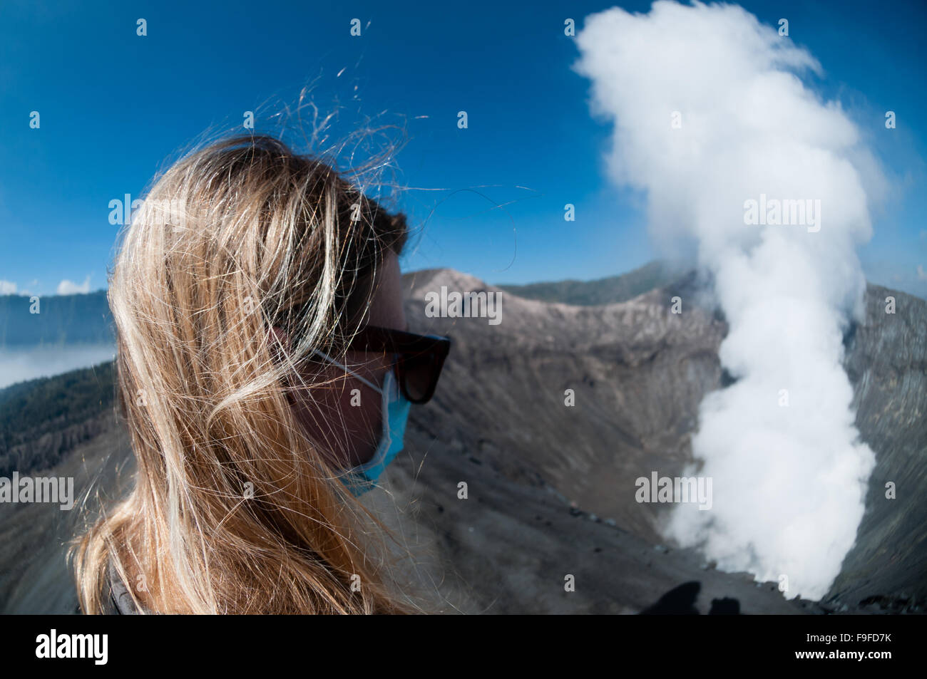 Woman watching volcano Bromo smoking under blue sky Stock Photo - Alamy