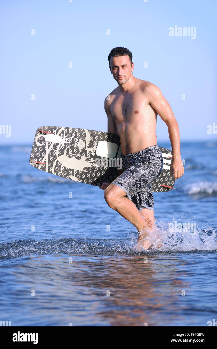 Portrait of a strong young surf man at beach on sunset in a ...