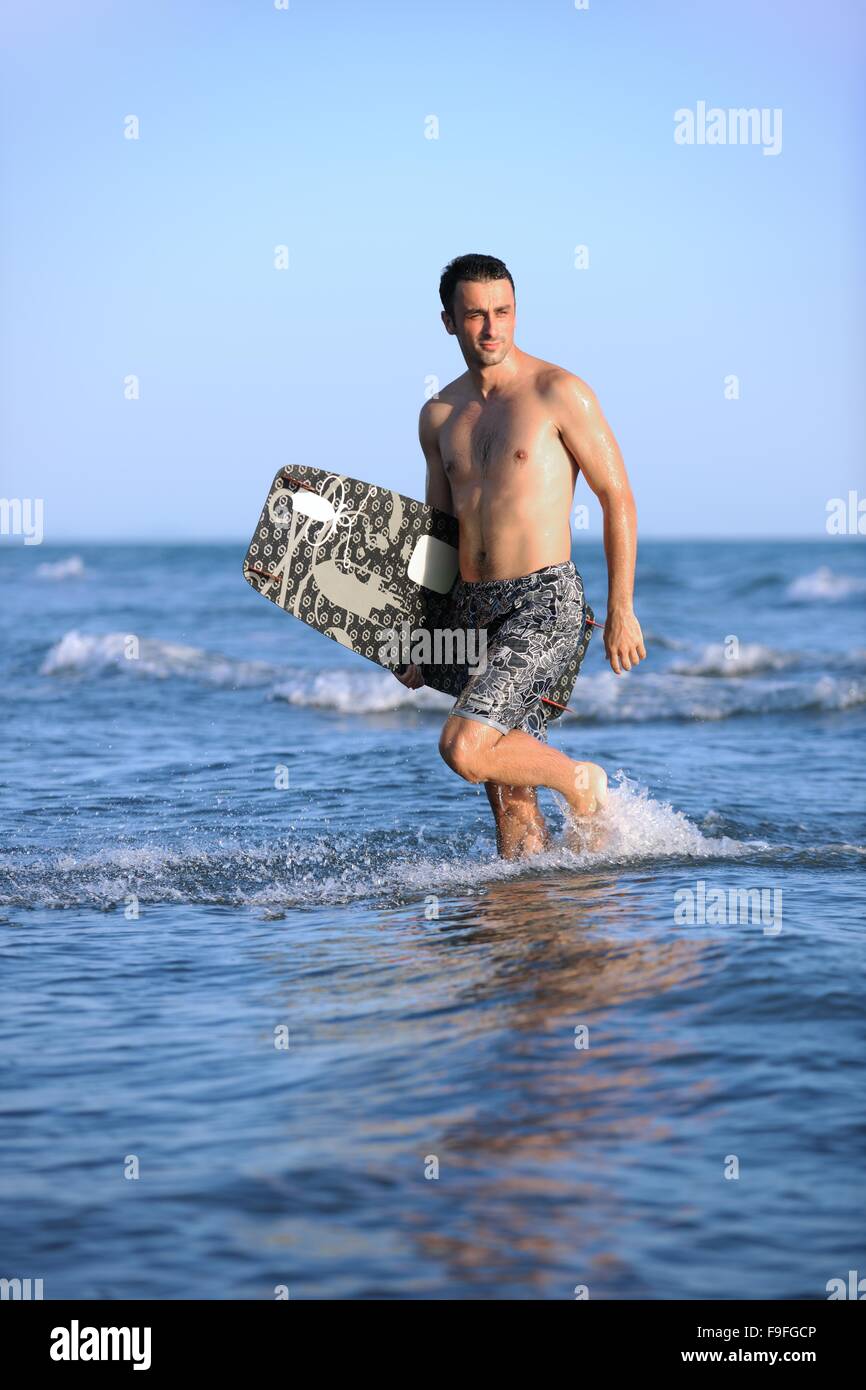 Portrait of a strong young surf man at beach on sunset in a ...