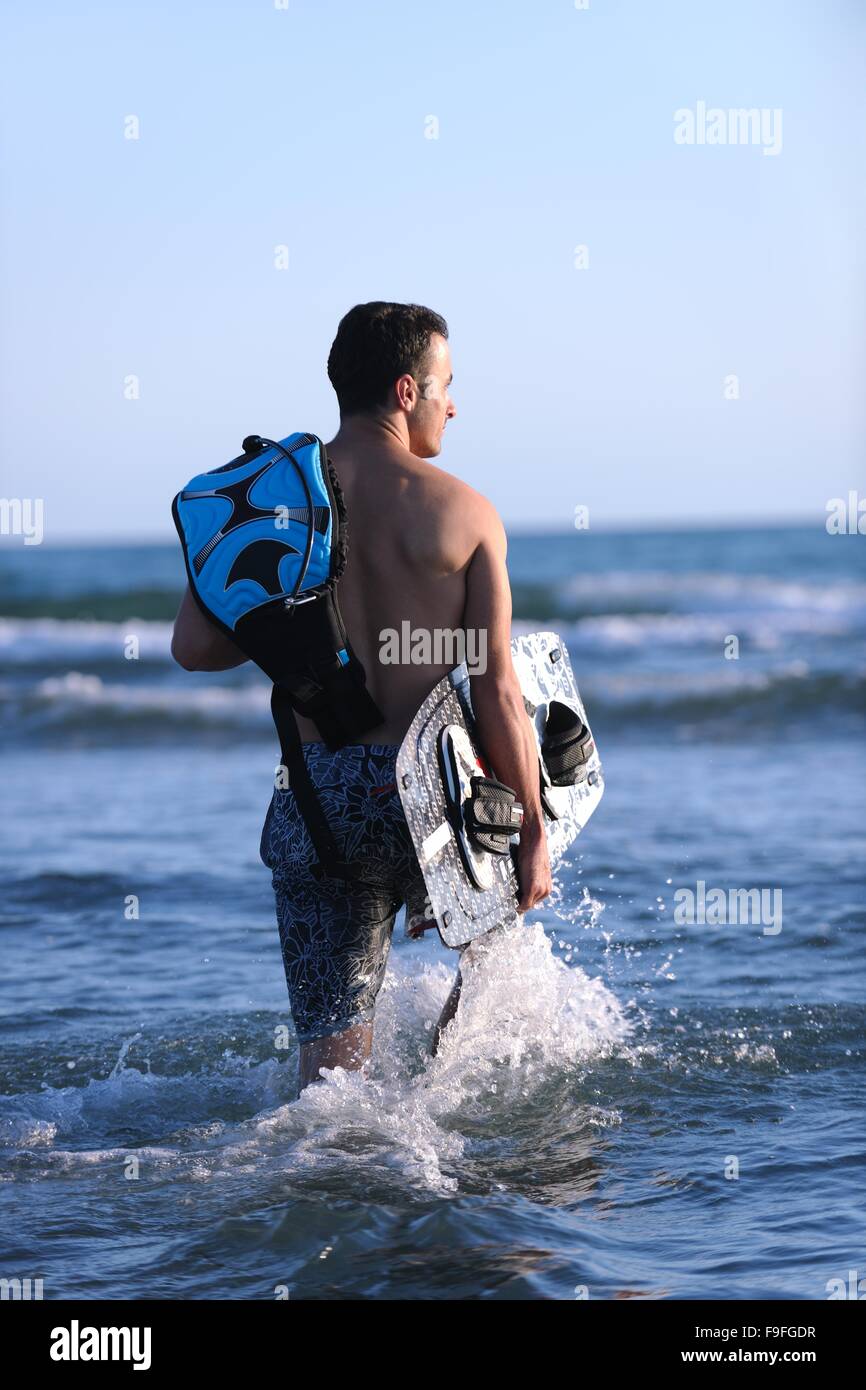 Portrait of a strong young surf man at beach on sunset in a ...