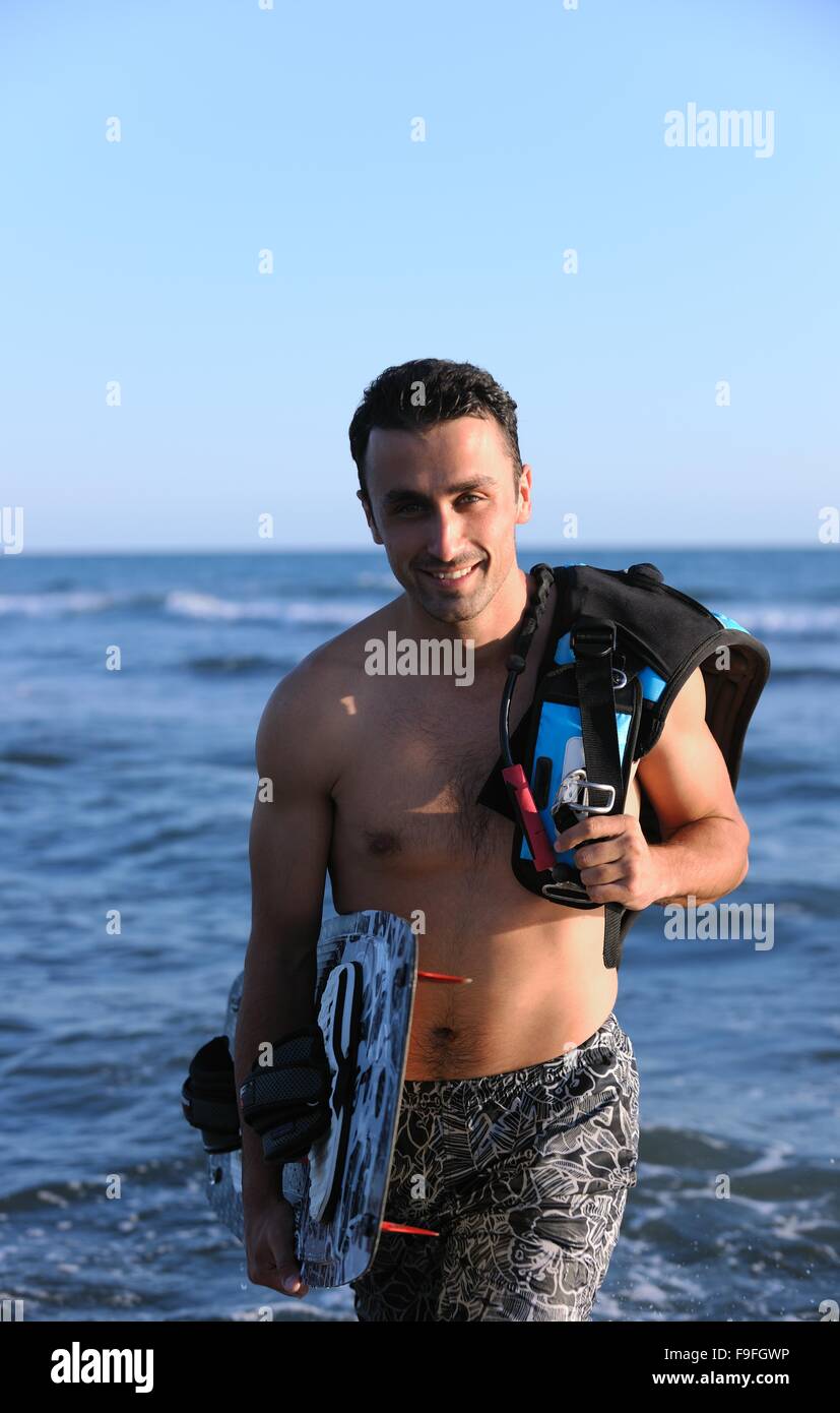 Portrait of a strong young surf man at beach on sunset in a ...