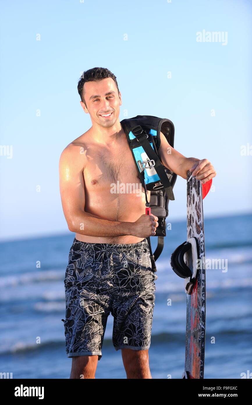 Portrait of a strong young surf man at beach on sunset in a ...