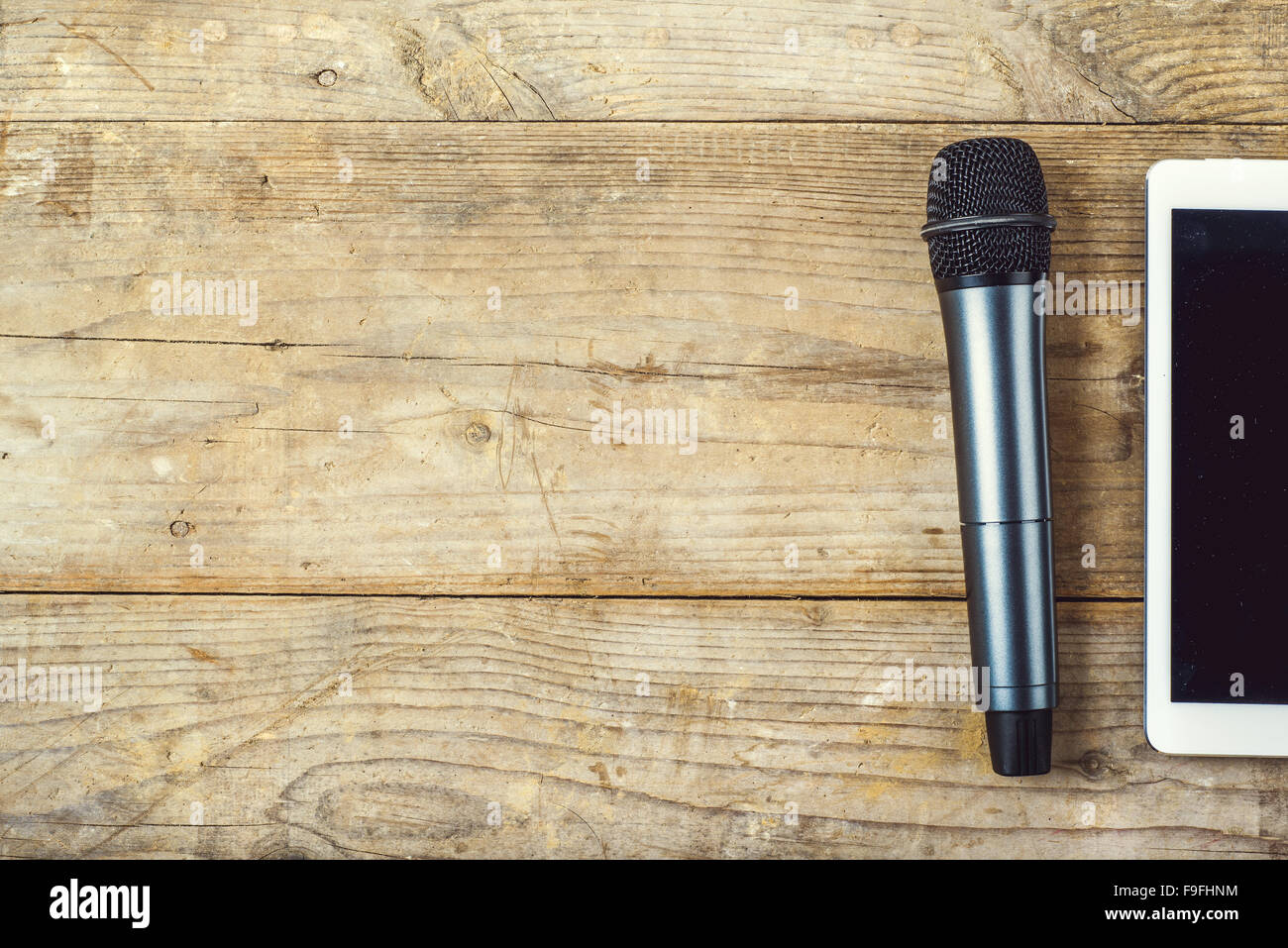 Tablet and microphone on a wooden office desk background. View from ...