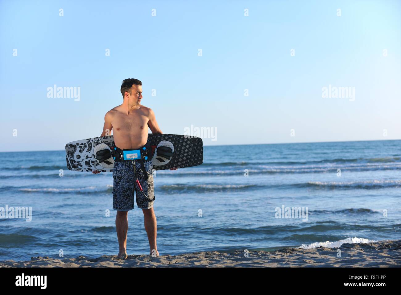 Portrait of a strong young surf man at beach on sunset in a ...