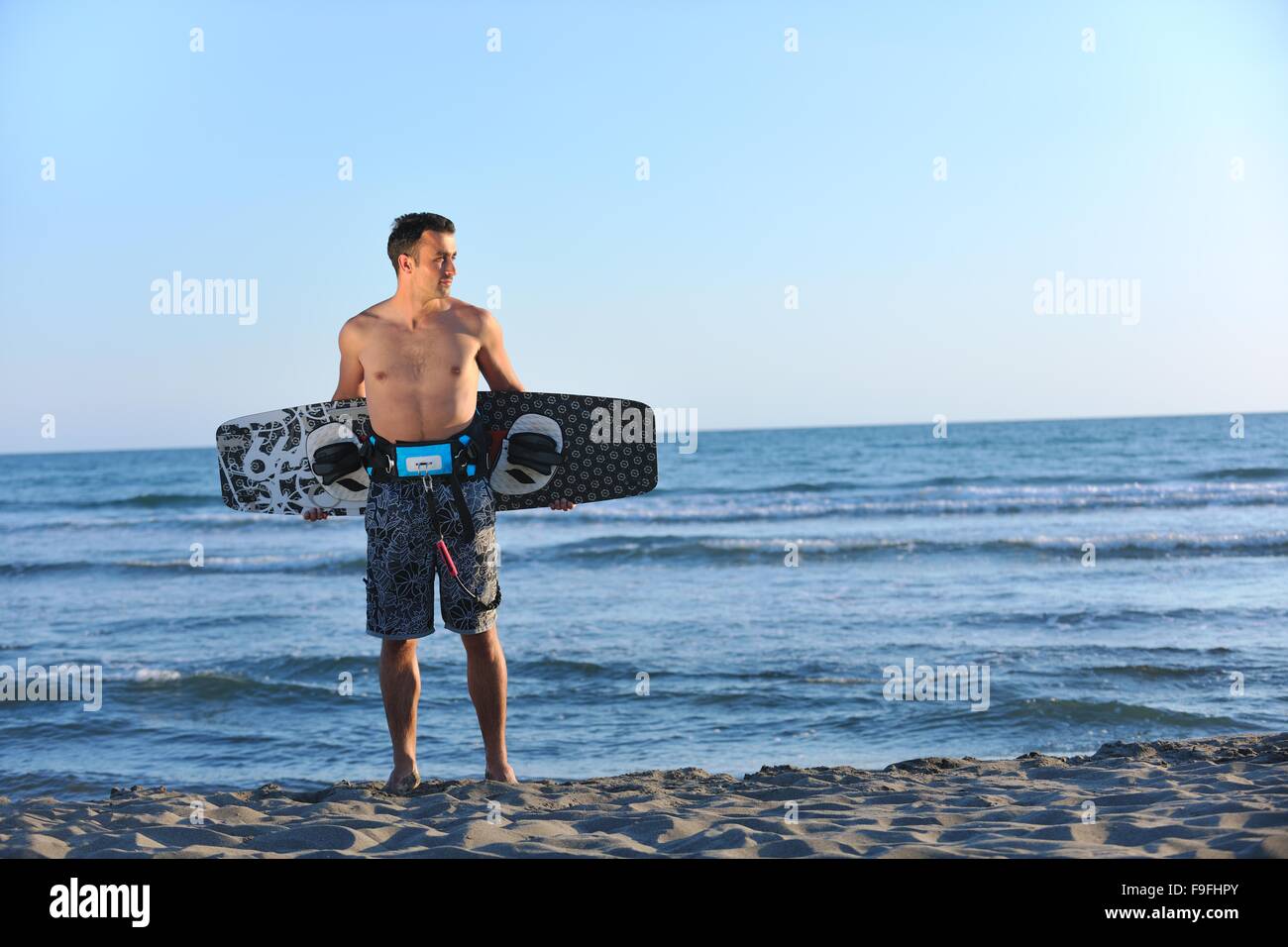 Portrait of a strong young surf man at beach on sunset in a ...