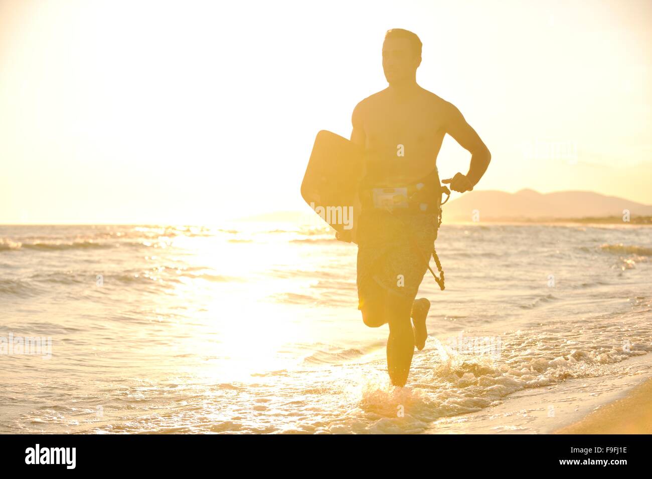Portrait of a strong young surf man at beach on sunset in a ...