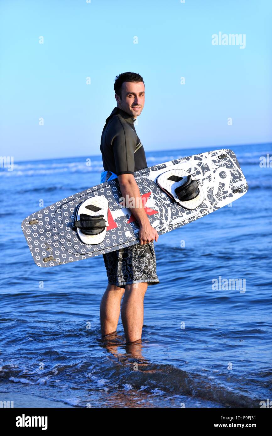 Portrait of a strong young surf man at beach on sunset in a ...