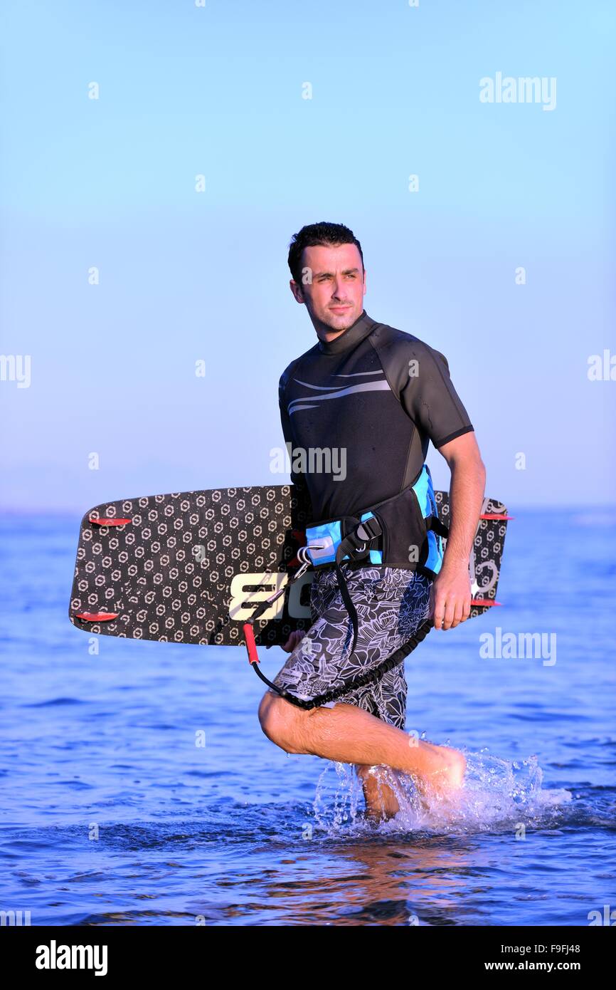 Portrait of a strong young surf man at beach on sunset in a ...