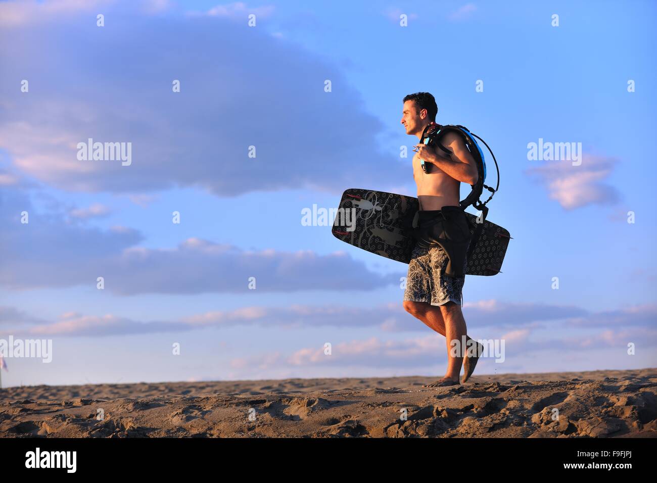 Portrait of a strong young surf man at beach on sunset in a ...