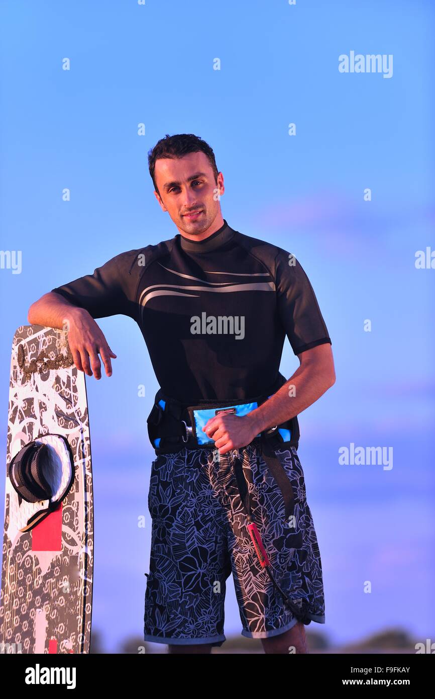 Portrait of a strong young surf man at beach on sunset in a ...