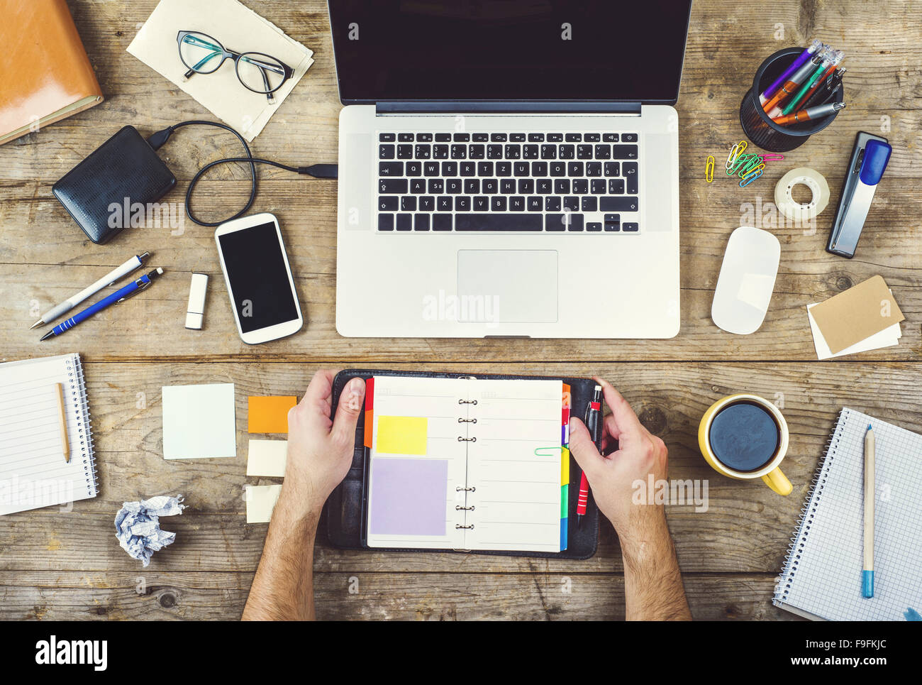 Mix of office supplies and gadgets on a wooden desk background. View ...