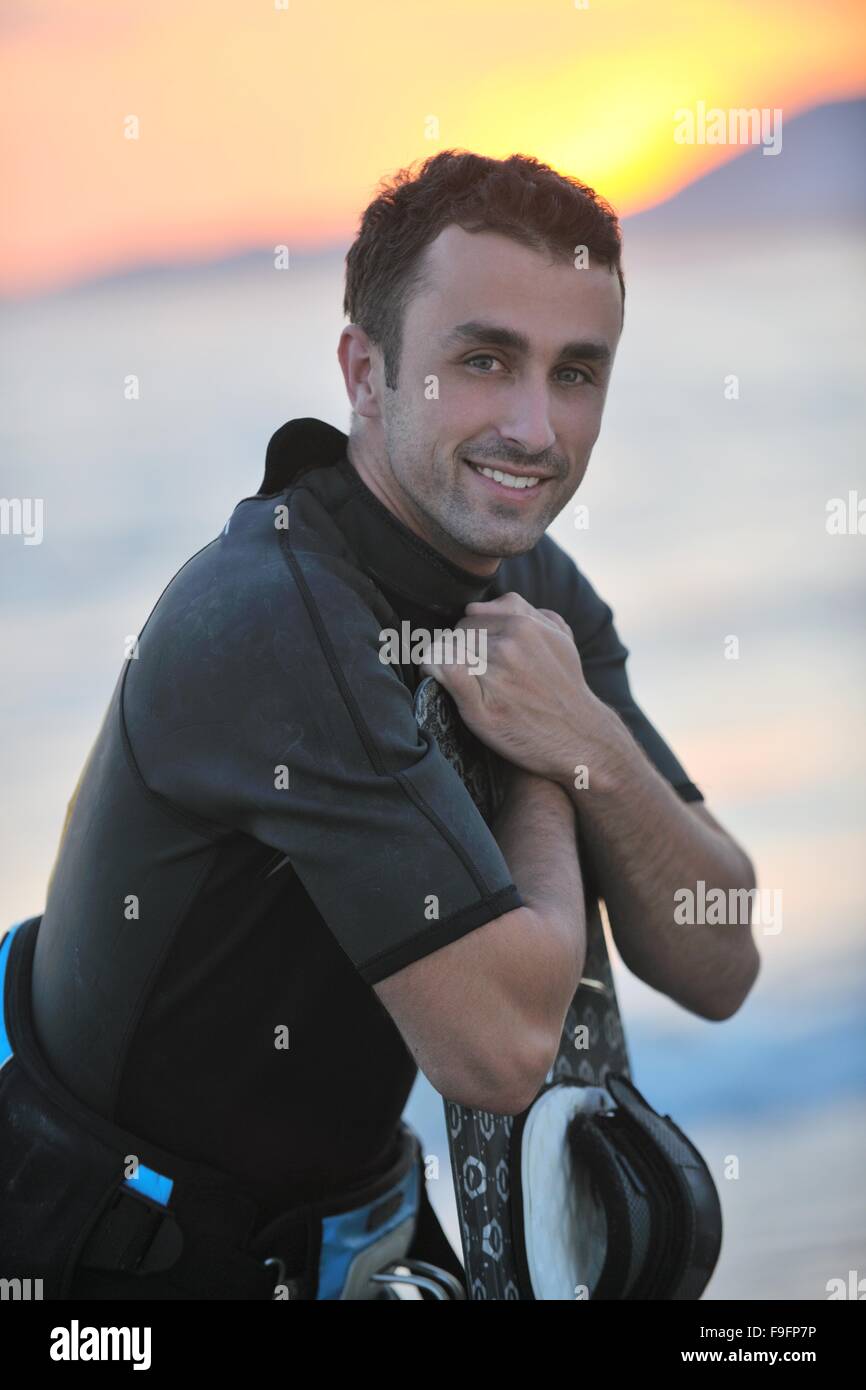 Portrait of a strong young surf man at beach on sunset in a ...