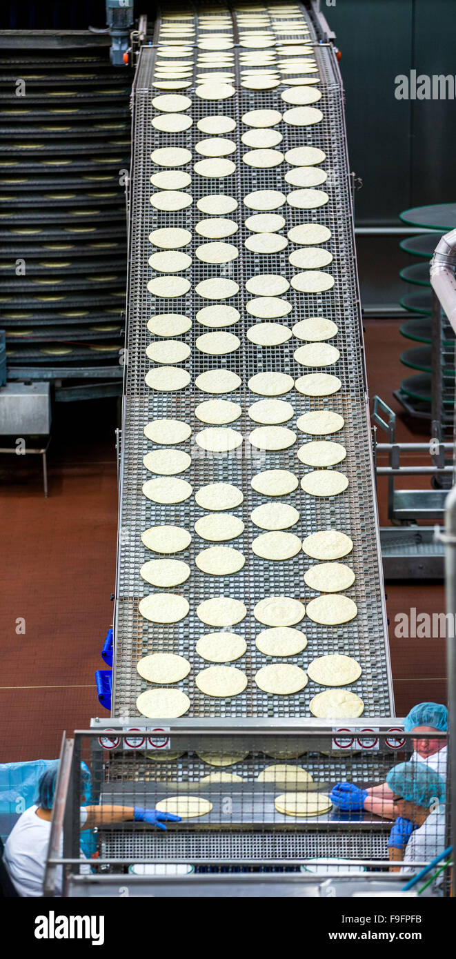 Staff check the production line that is topping frozen pizzas at the ...