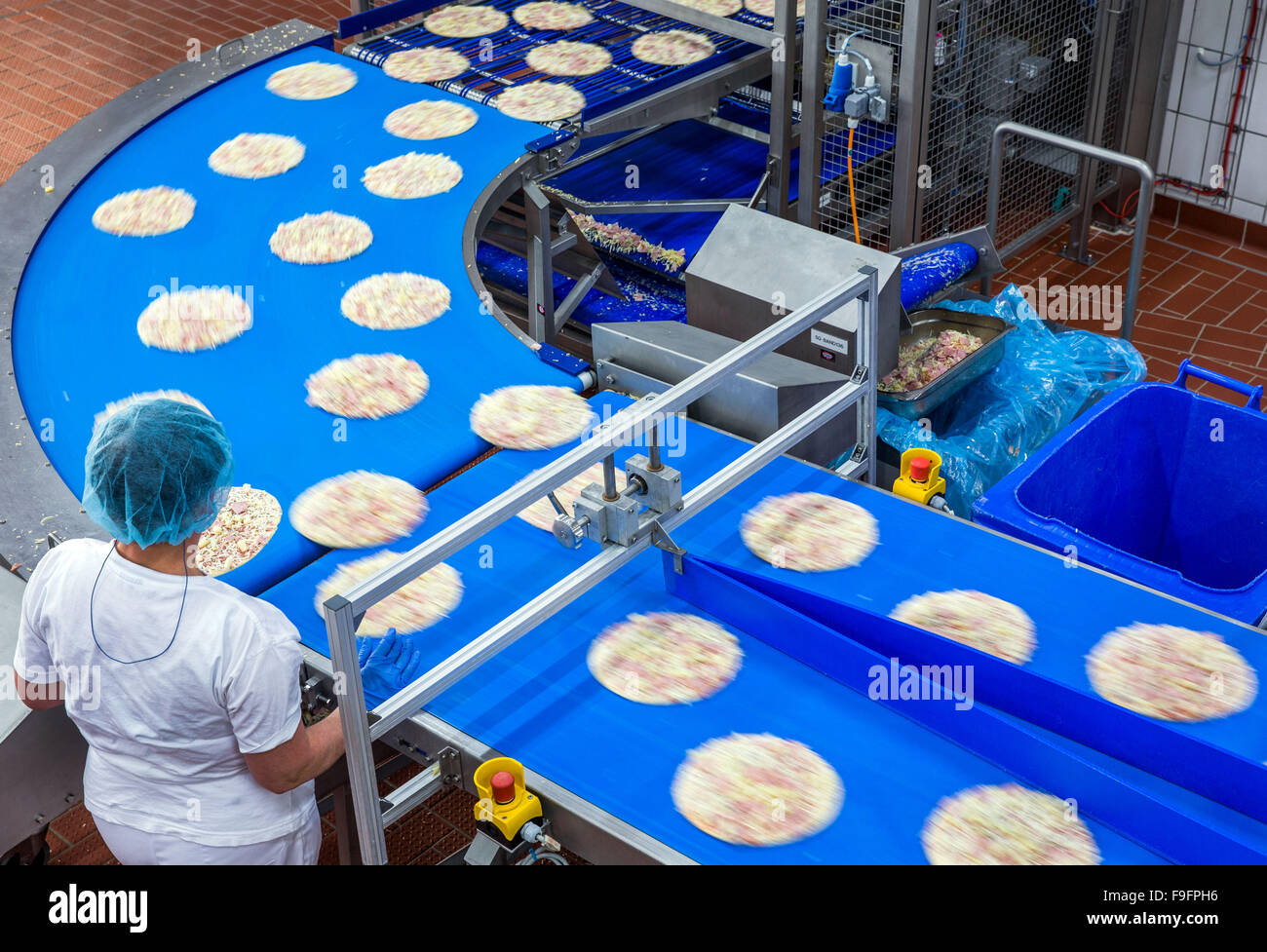 Staff on the production line put pinapple topping on frozen pizzas at ...