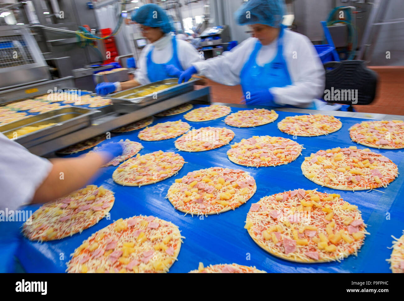 Staff on the production line put pinapple topping on frozen pizzas at ...