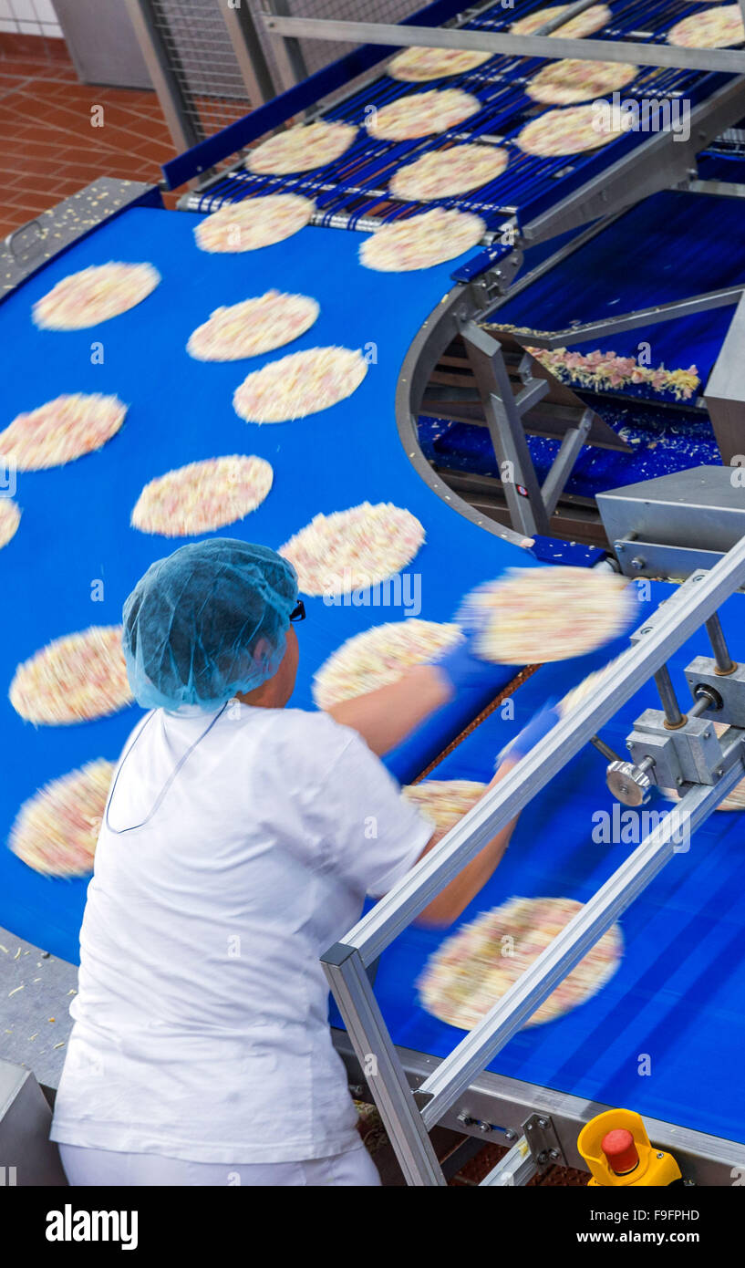 Staff on the production line put pinapple topping on frozen pizzas at ...