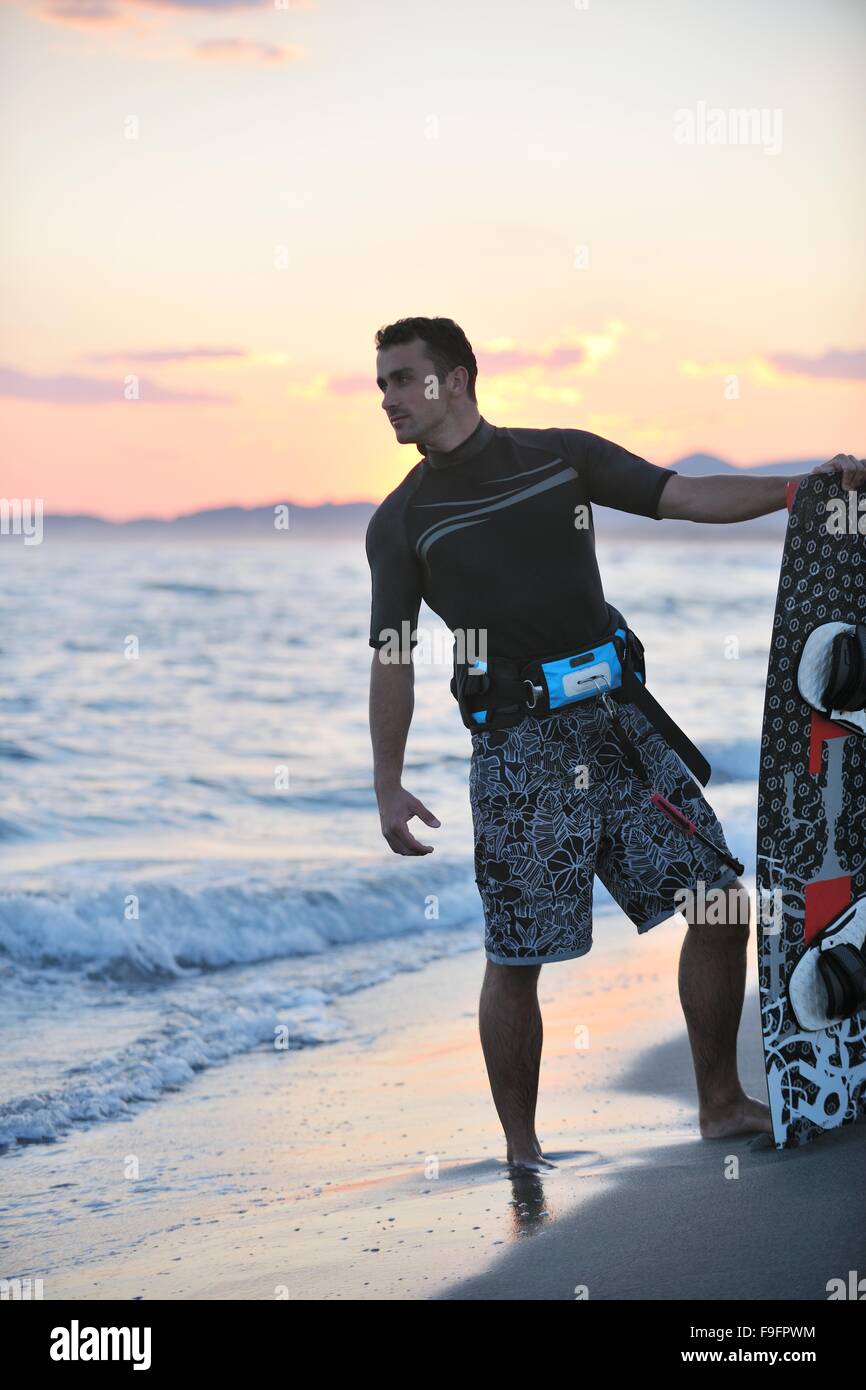 Portrait of a strong young surf man at beach on sunset in a ...
