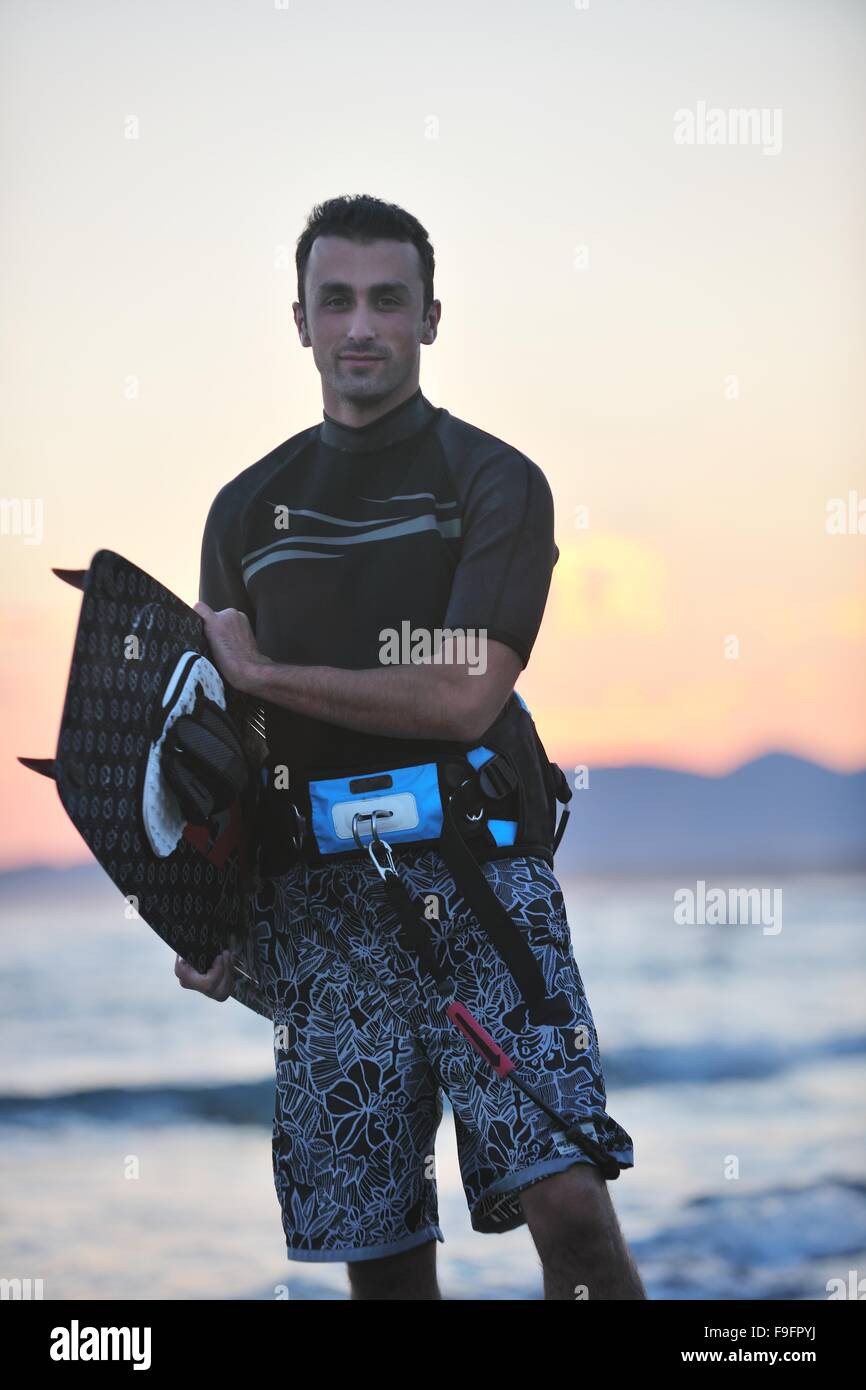 Portrait of a strong young surf man at beach on sunset in a ...