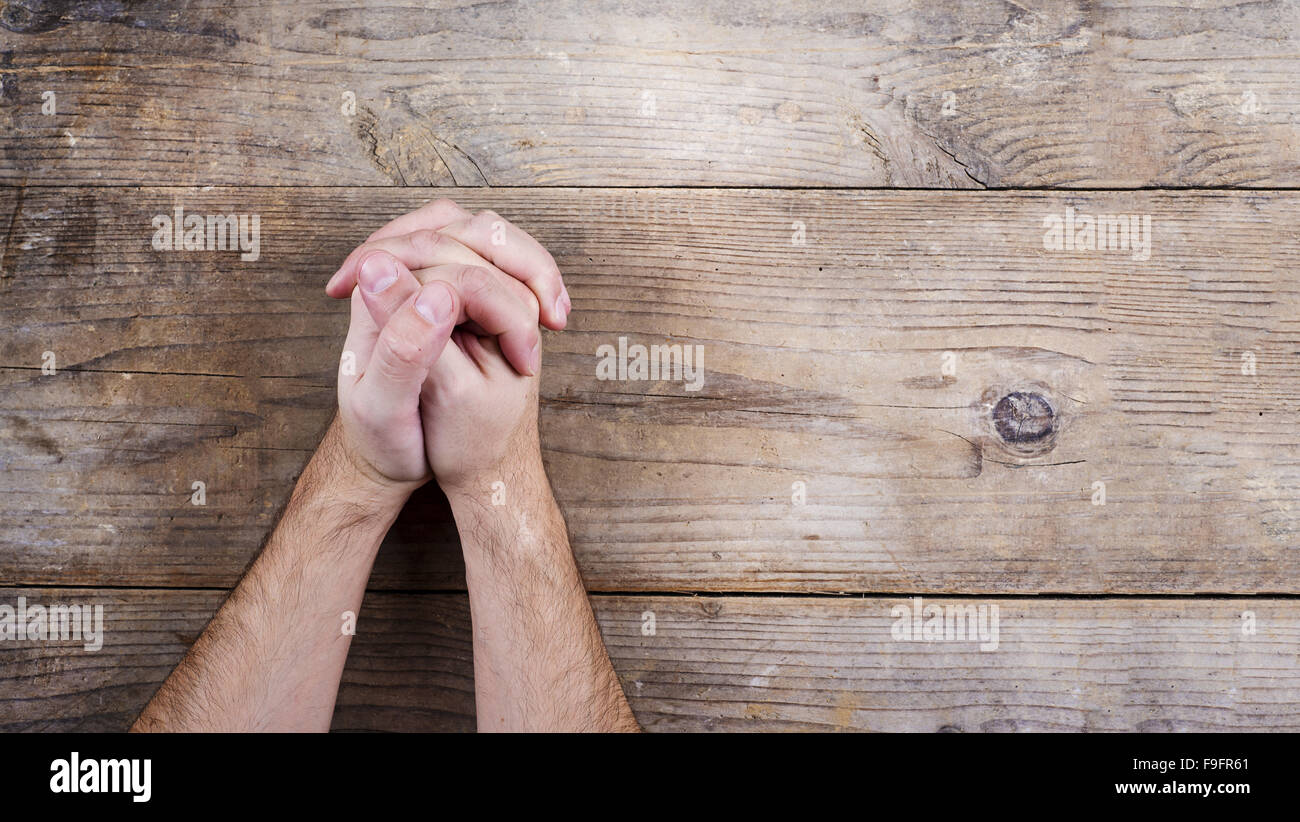 Hands of praying young man on a wooden desk background Stock Photo - Alamy