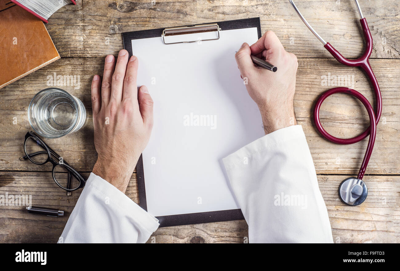 Hands of unrecognizable doctor writing on a blank sheet of paper ...