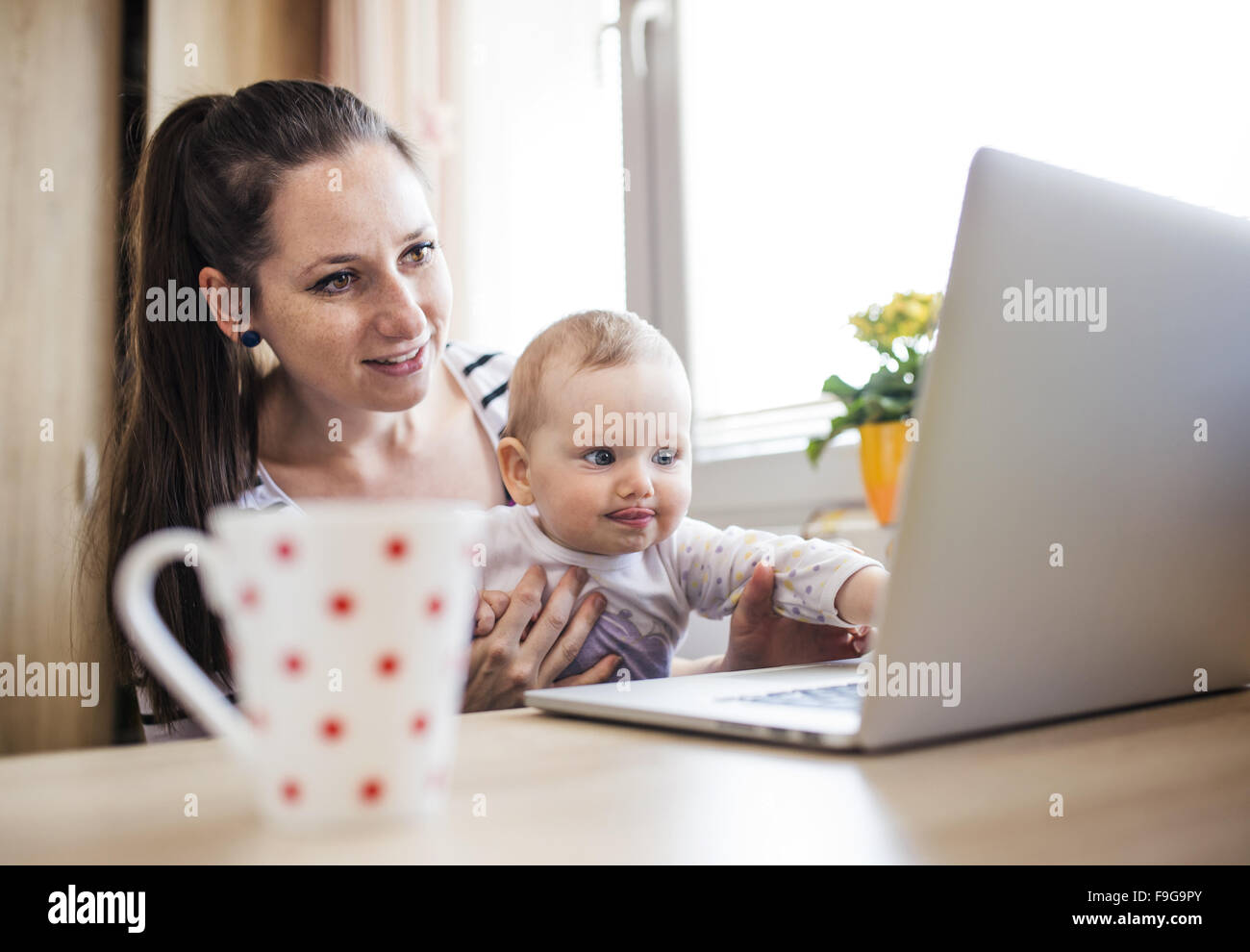 Young mother in home office with computer and her daughter Stock Photo ...