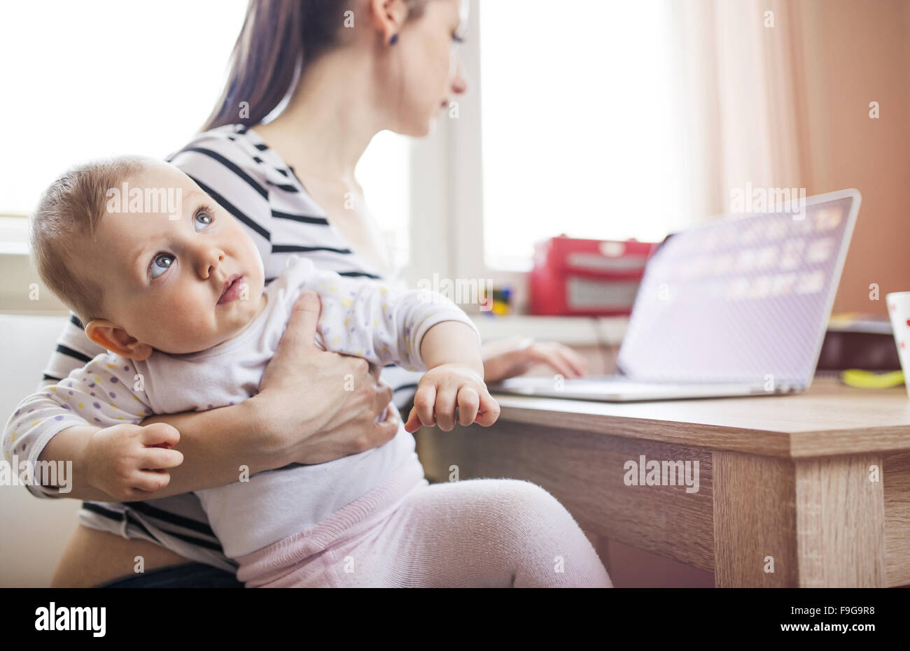 Young mother in home office with computer and her daughter Stock Photo ...