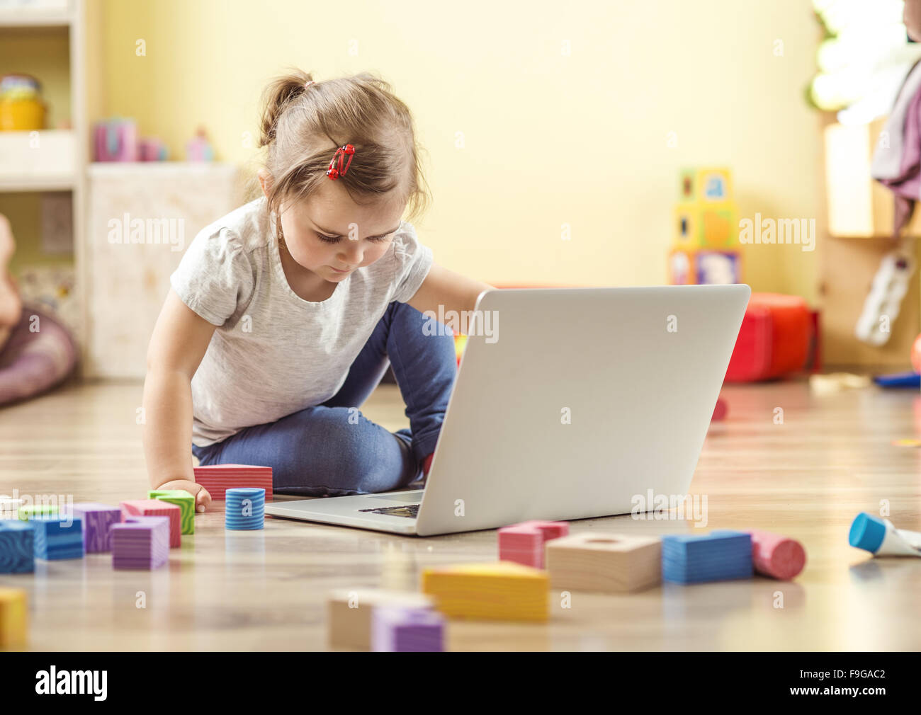 Beautiful little girl in her room playing with notebook Stock Photo - Alamy