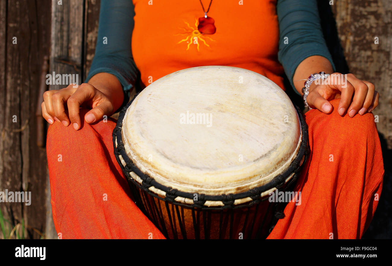 Young lady drummer with her djembe drum on rustic wooden door ...