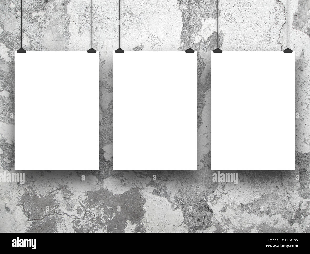 Close-up of three hanged paper sheet frames with clips on grey cracked ...