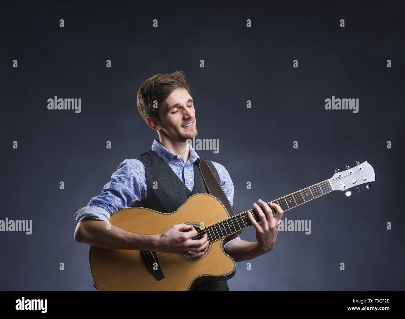 Young handsome guitar player. Studio shot on black background Stock ...