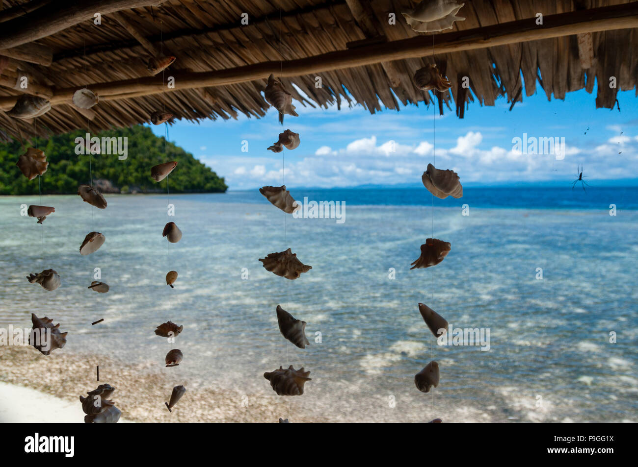Shells Hanging From Bamboo Roof in front of crystal clear water and ...