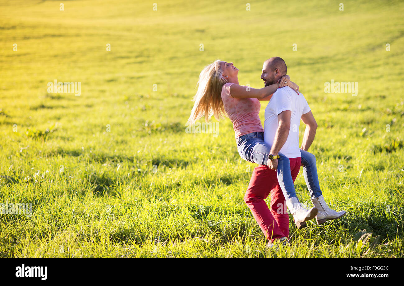 Happy young couple having fun outside on a meadow Stock Photo - Alamy