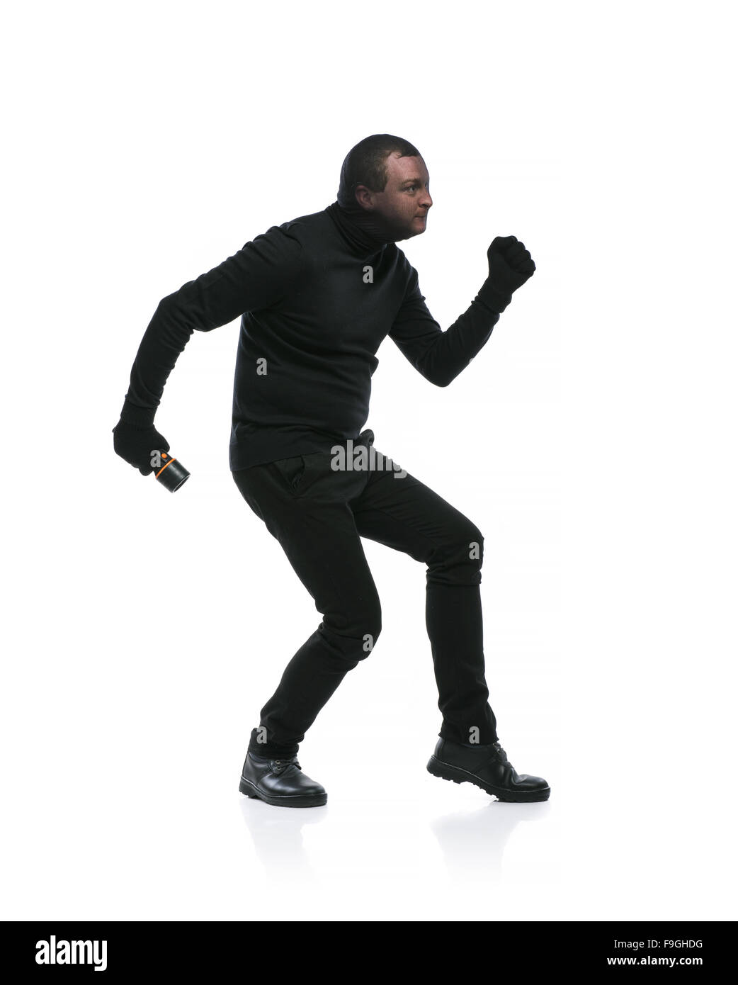 Thief in action with balaclava on his face, dressed in black. Studio ...