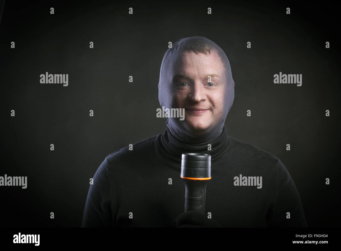 Thief in action with balaclava on his face, dressed in black. Studio ...