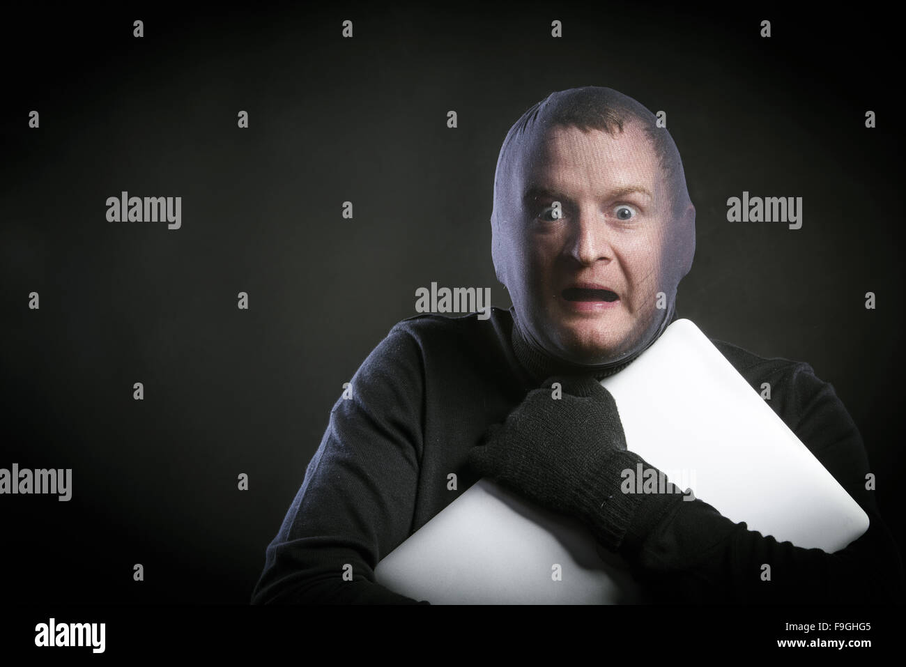 Thief in action with balaclava on his face, dressed in black. Studio ...