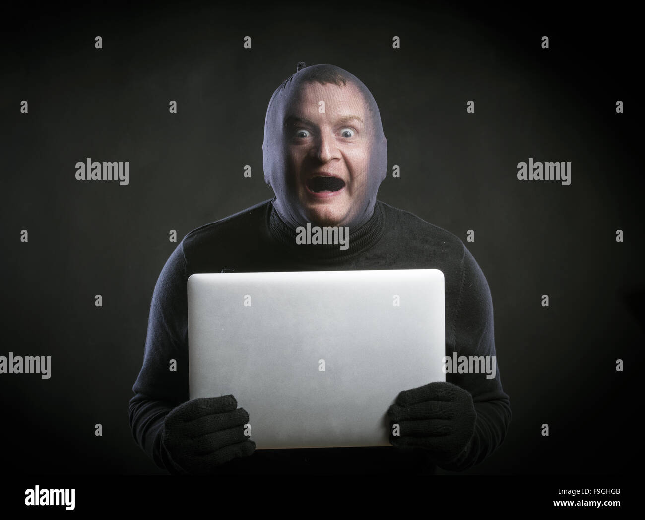 Thief in action with balaclava on his face, dressed in black. Studio ...