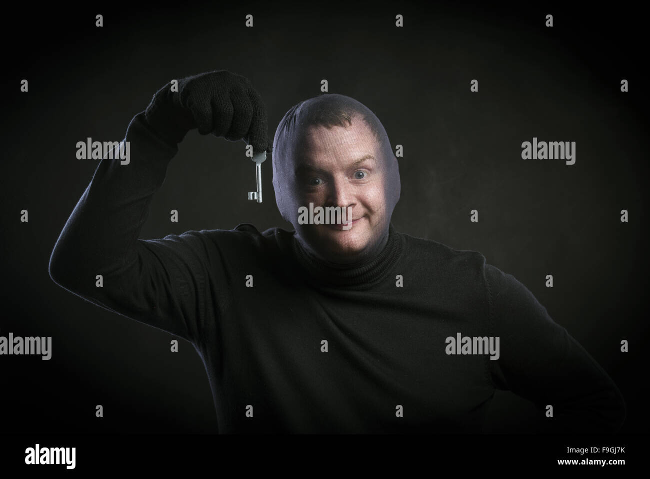 Thief in action with balaclava on his face, dressed in black. Studio ...