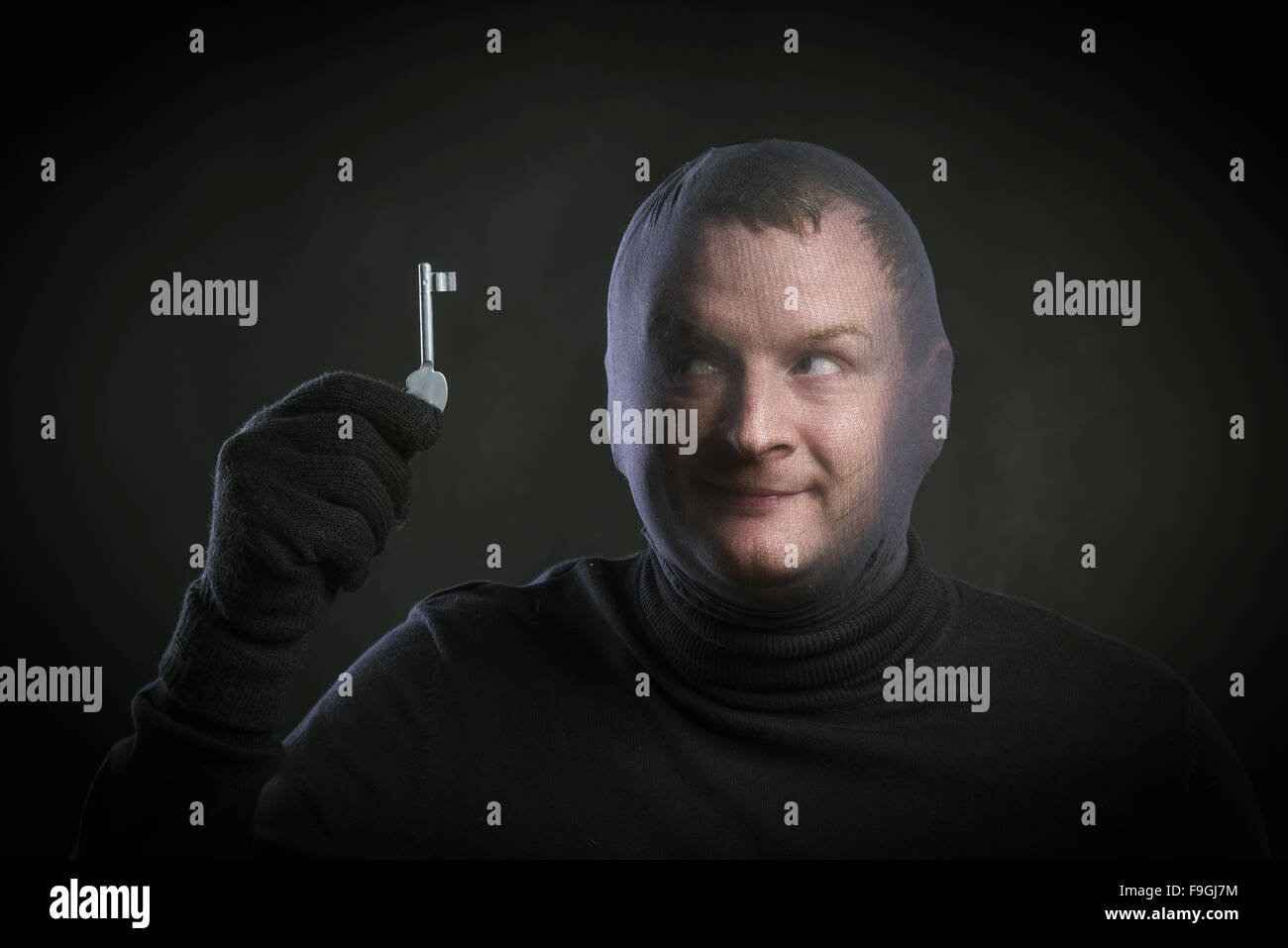 Thief in action with balaclava on his face, dressed in black. Studio ...