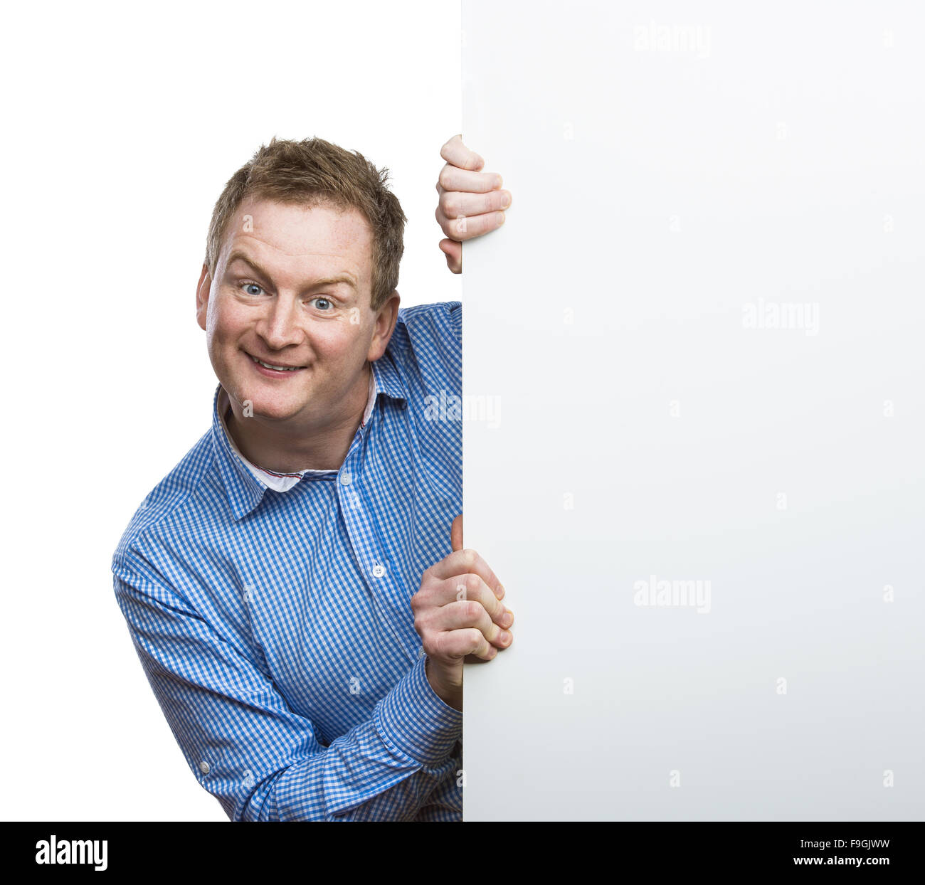 Young man making funny face, holding a blank sign board. Studio shot on ...