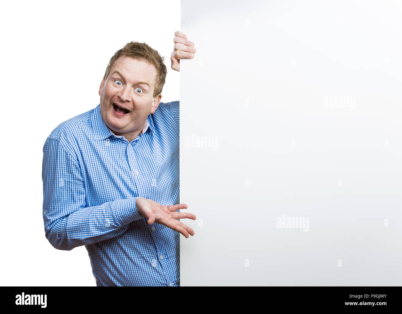 Young man making funny face, holding a blank sign board. Studio shot on ...
