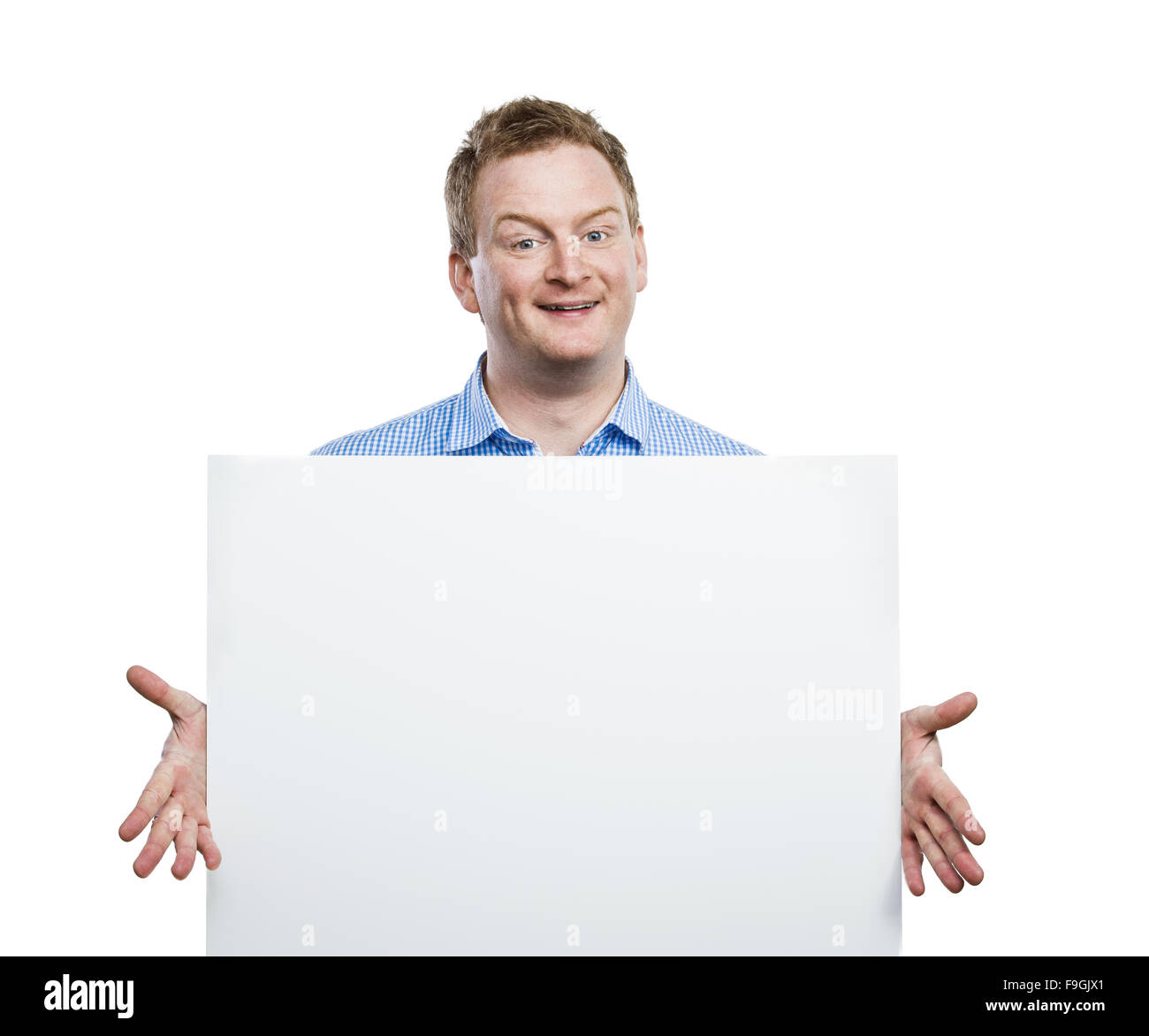 Young man making funny face, holding a blank sign board. Studio shot on ...