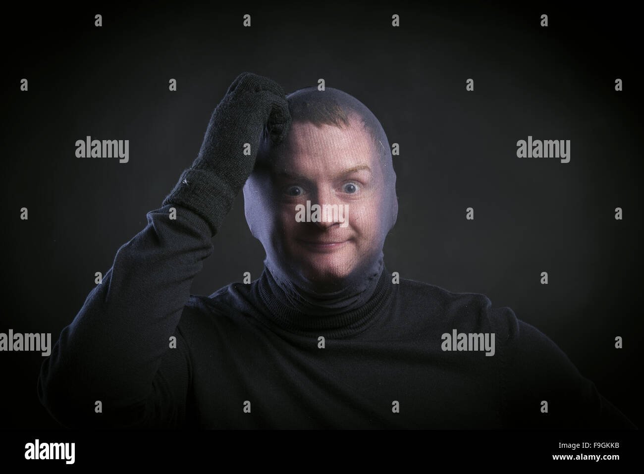 Thief in action with balaclava on his face, dressed in black. Studio ...